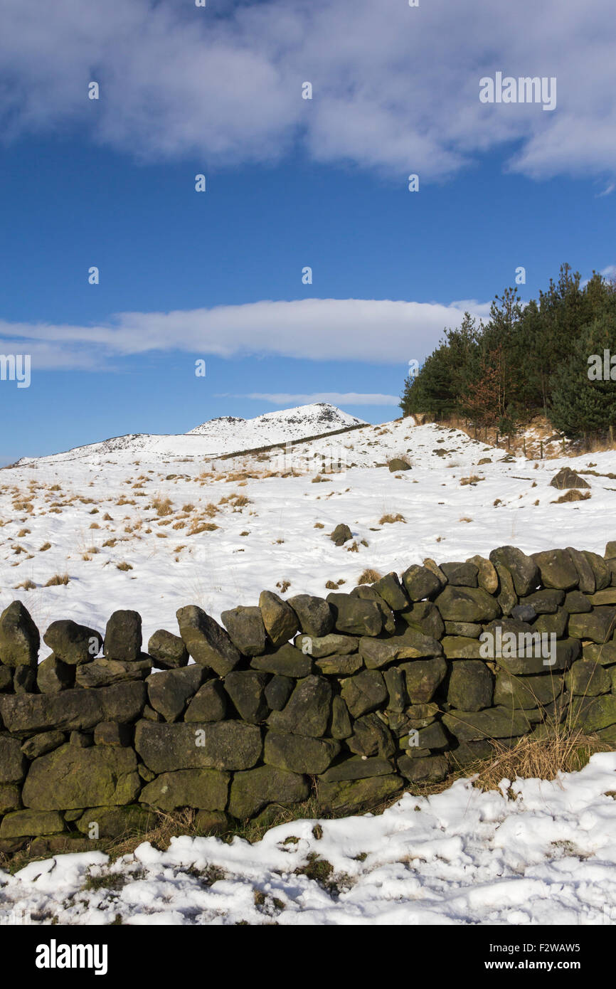 Snow covered hill beyond a dry stone wall near Dovestone reservoir ...
