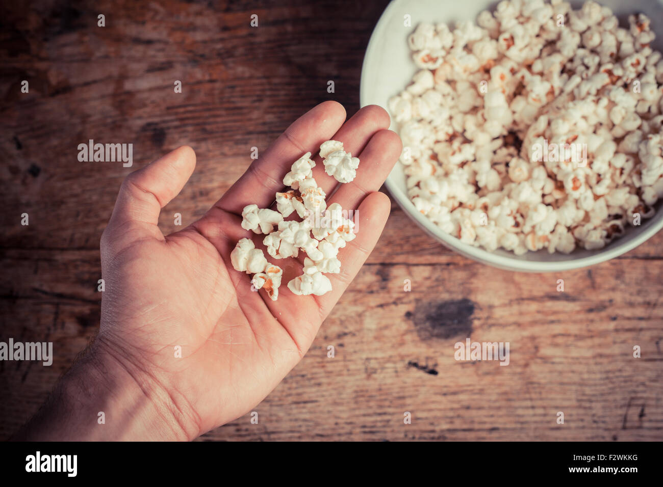 A hand taking popcorn from a large bowl Stock Photo - Alamy