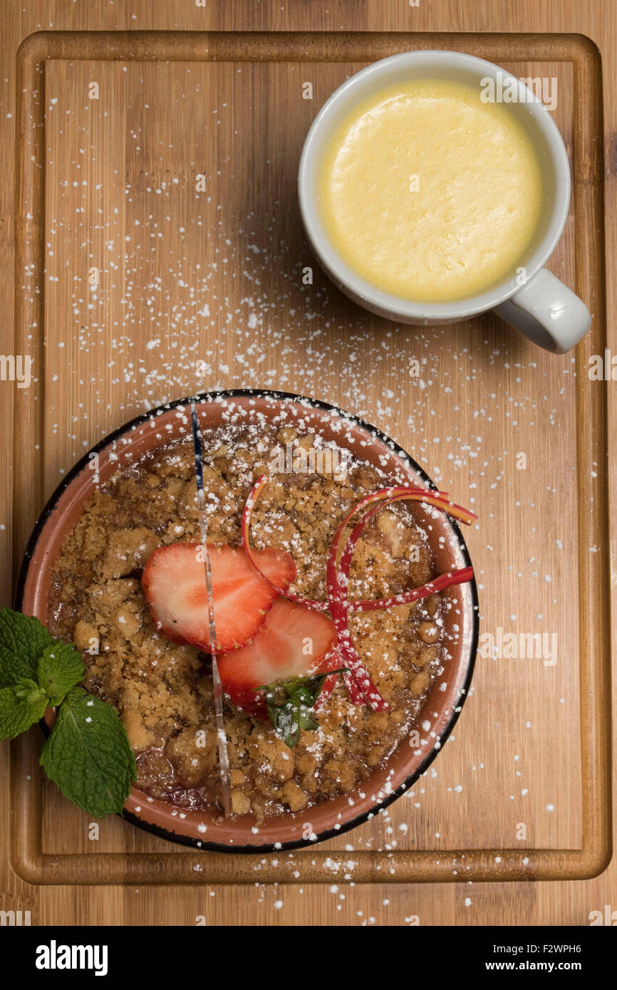 Apple crumble dessert with custard and strawberry garnish Stock Photo ...