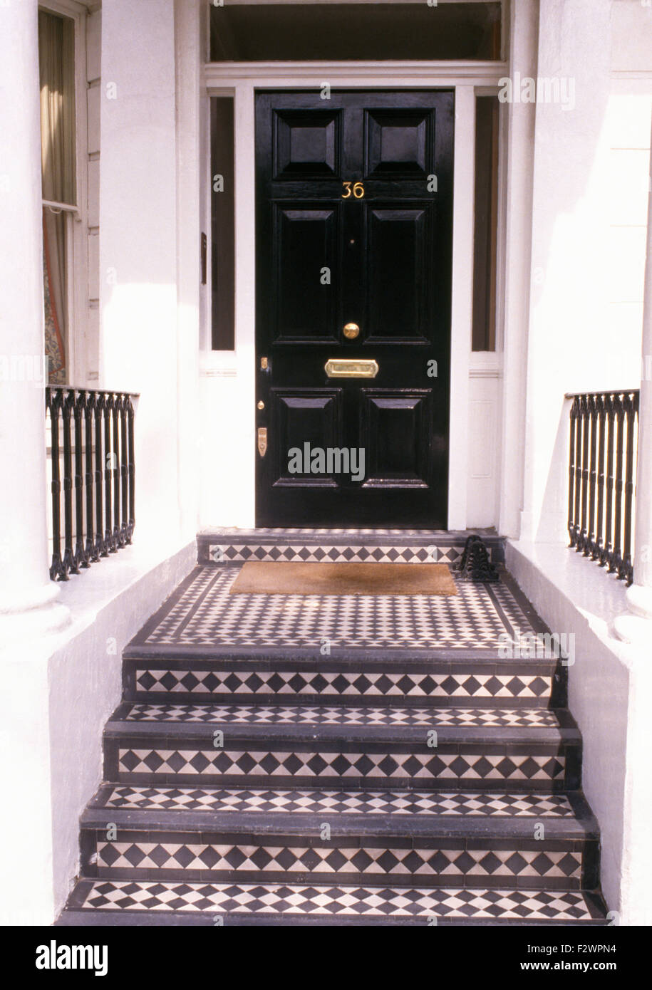 Newly renovation black+white tiled steps leading to black front door of ...