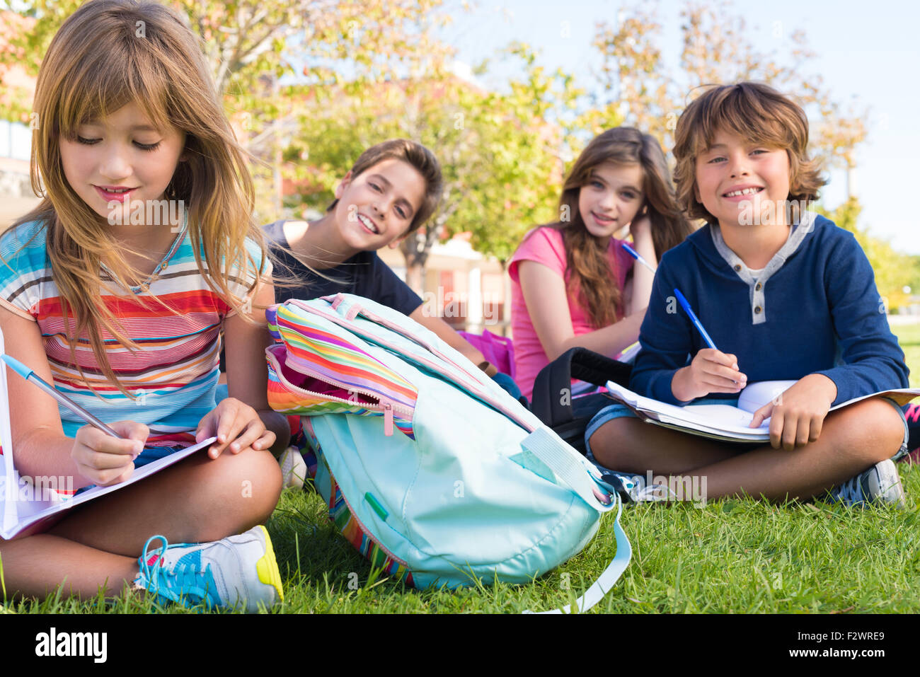 Group of little students sitting on the grass at school Stock Photo - Alamy