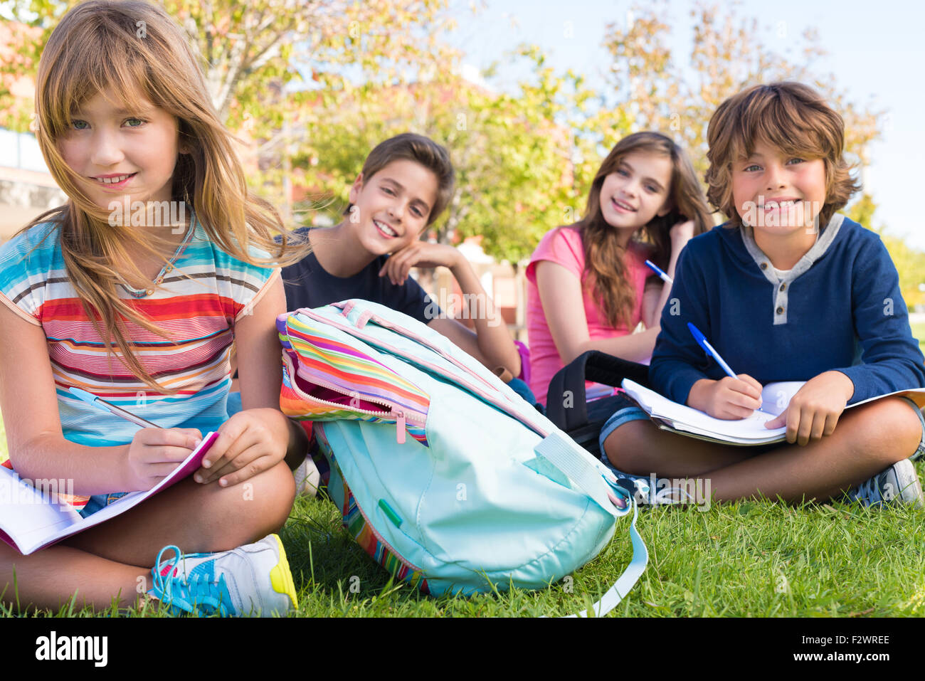 Group of little students sitting on the grass at school Stock Photo - Alamy