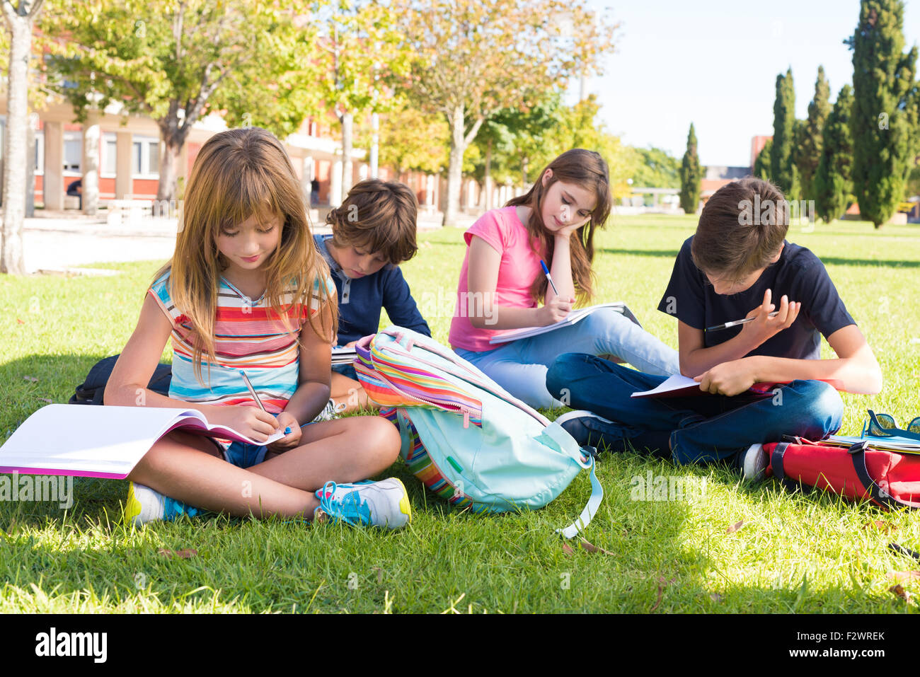 Group of little students sitting on the grass at school Stock Photo - Alamy