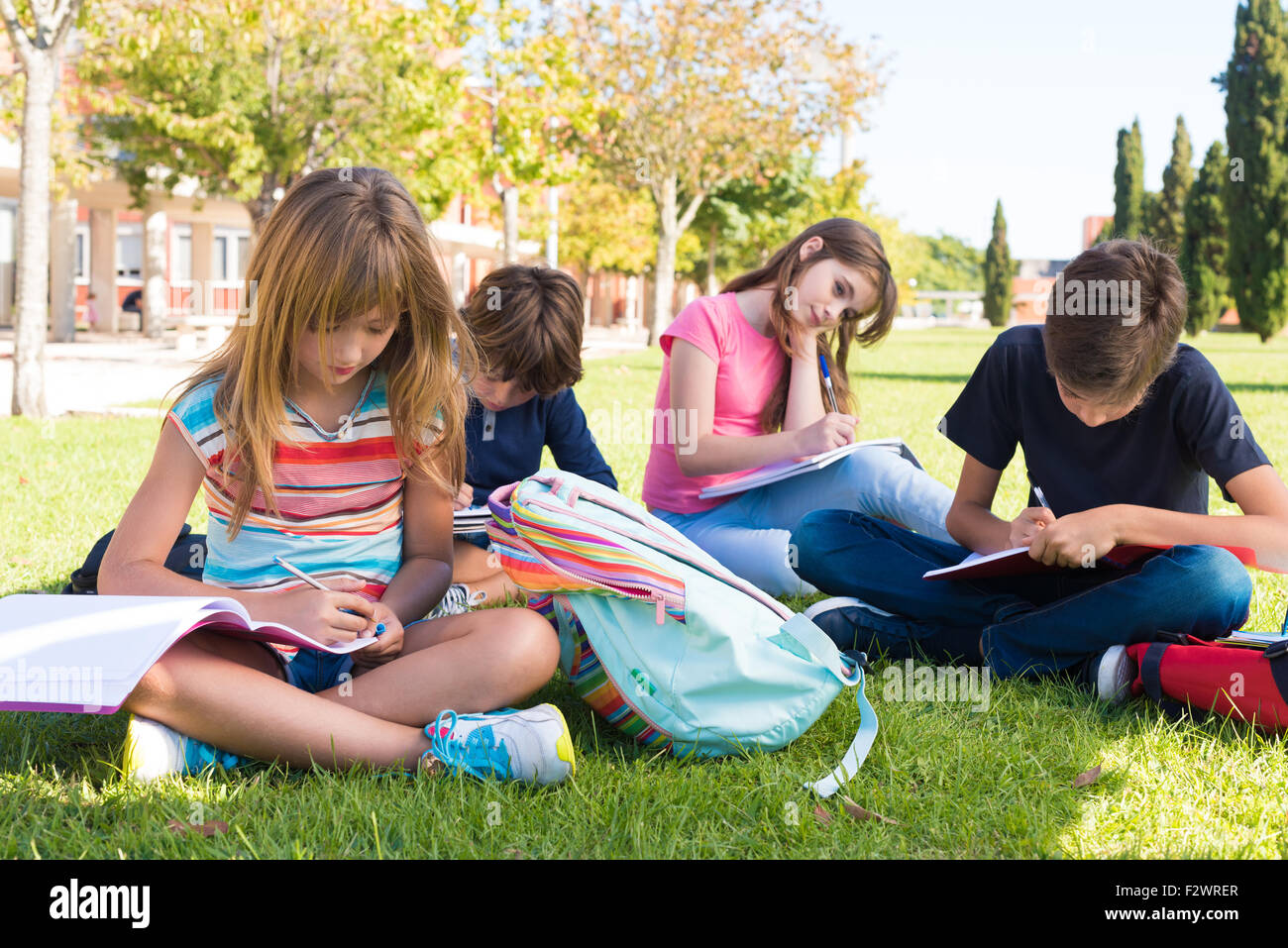 Group of little students sitting on the grass at school Stock Photo - Alamy