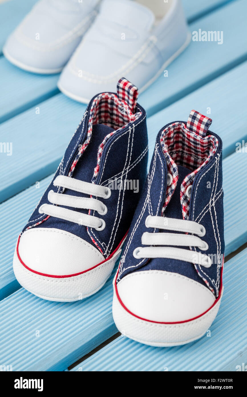 Pairs of dark blue,white baby sneakers and blue baby shoes over blue ...