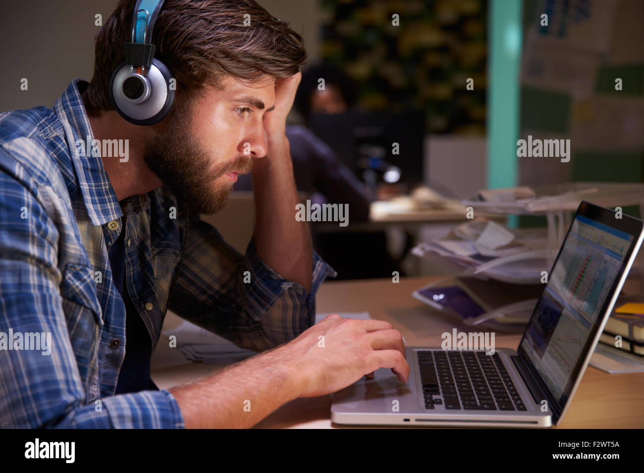 Office Workers At Desks Working Late On Laptops Stock Photo - Alamy