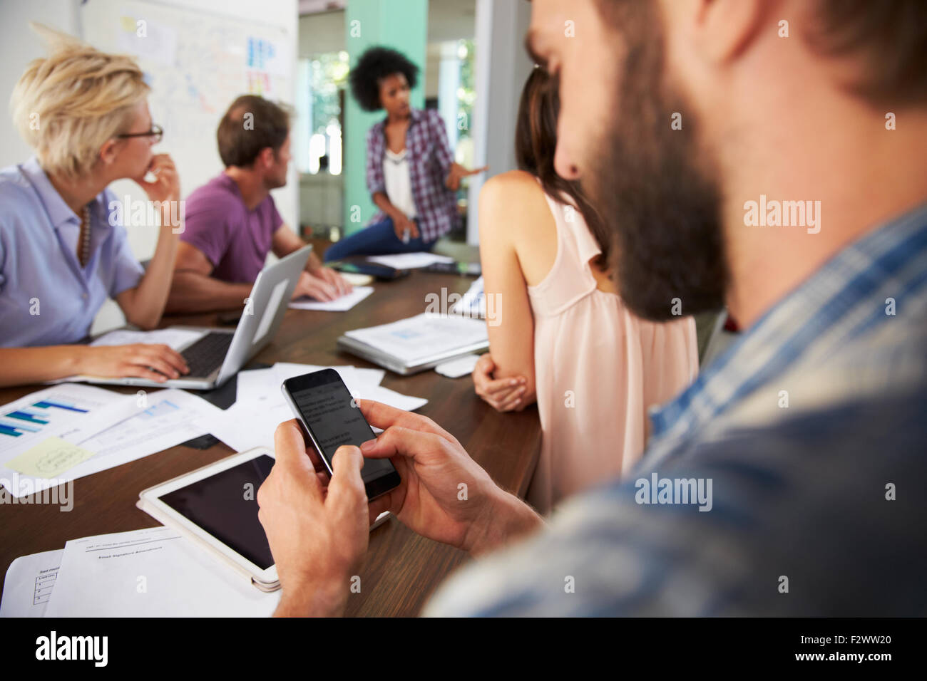 Businessman Texting During Meeting In Office Stock Photo - Alamy