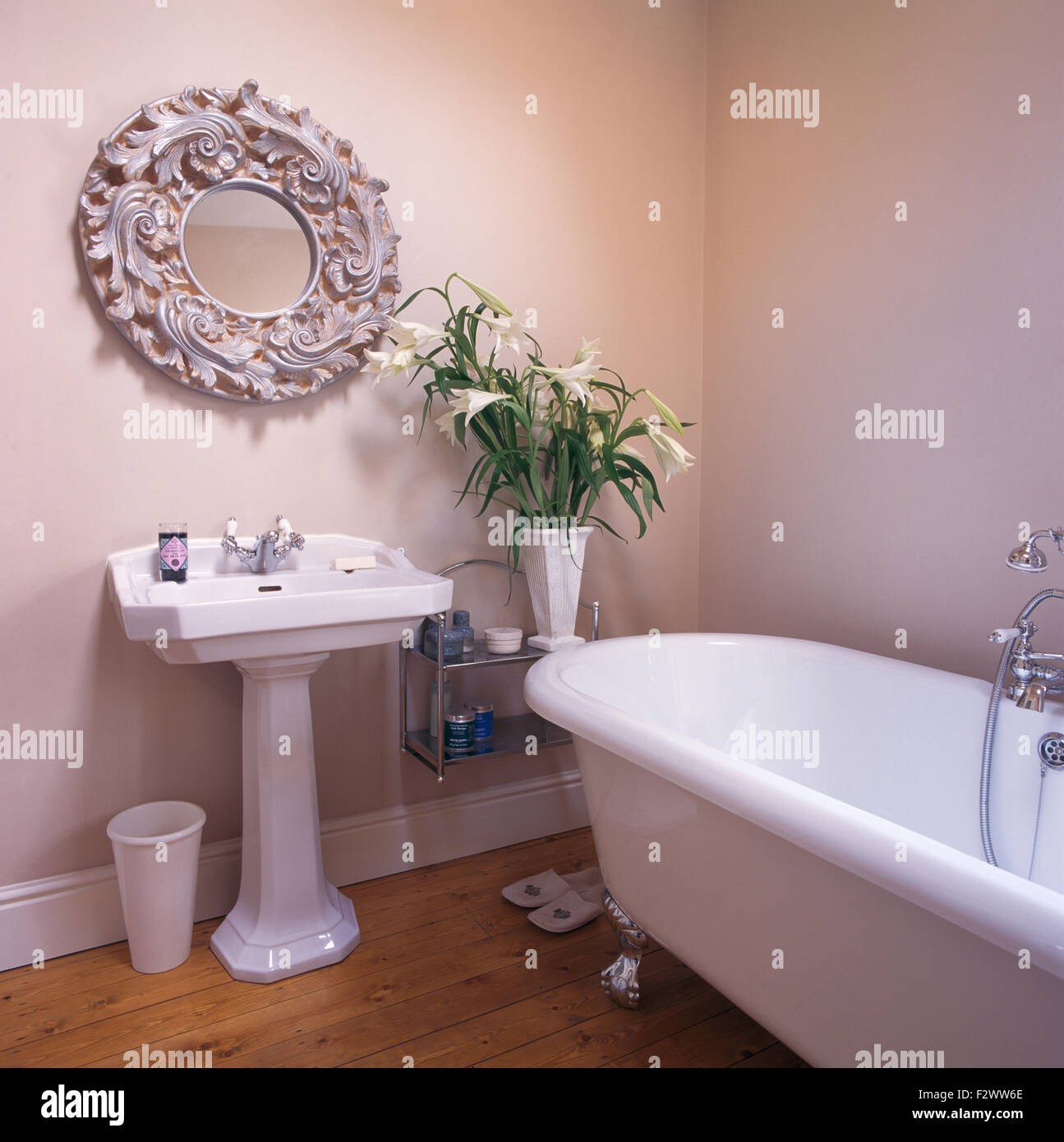 Ornate circular mirror above pedestal basin in nineties bathroom with ...