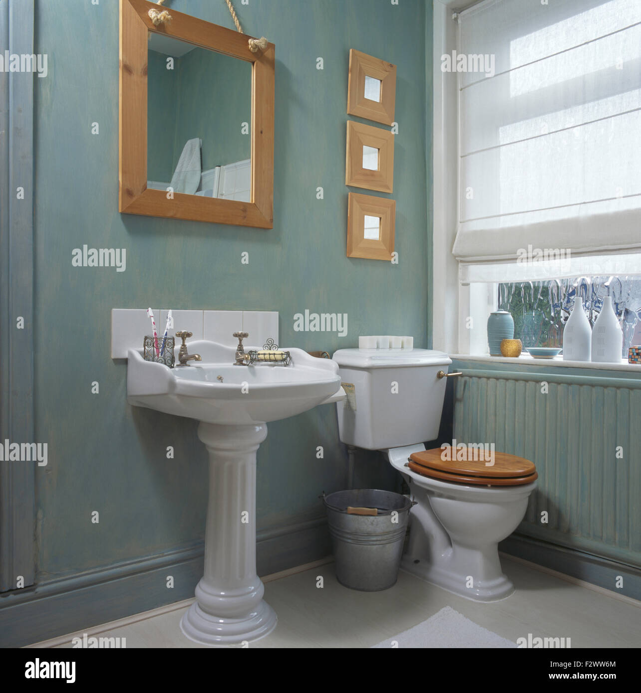 Wooden mirror above pedestal basin in pale turquoise bathroom with ...