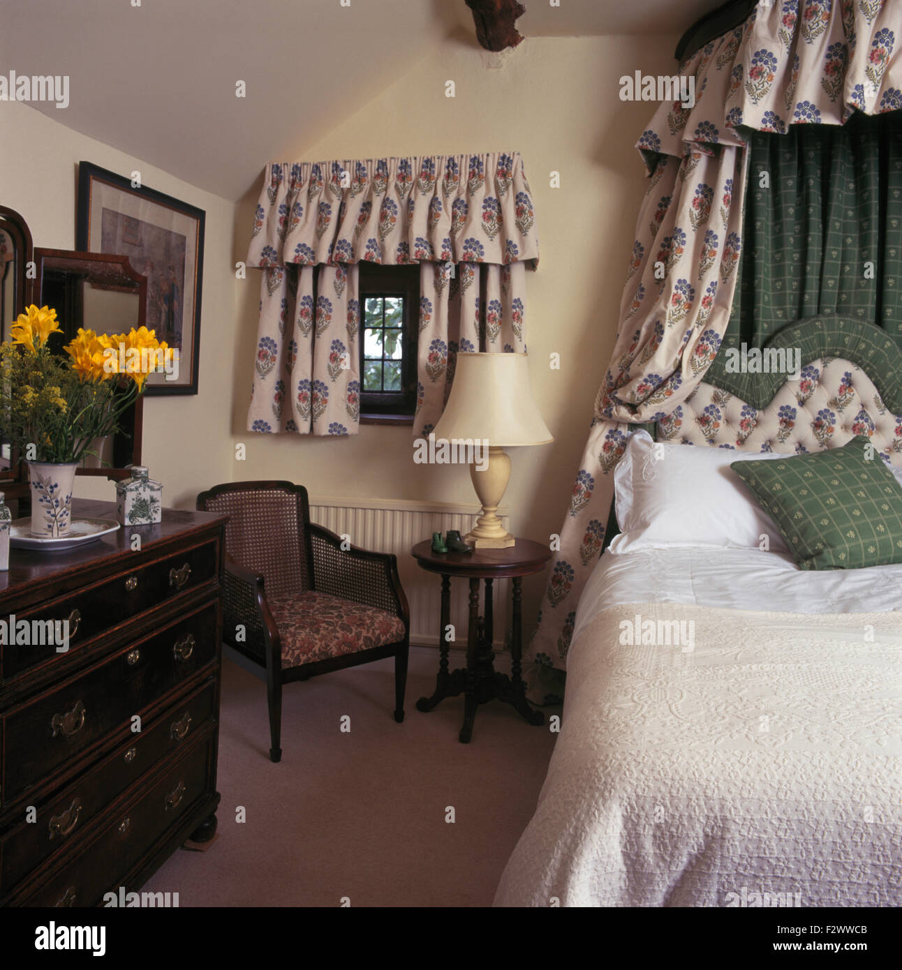 Patterned curtains on window and half tester bed in nineties cottage ...