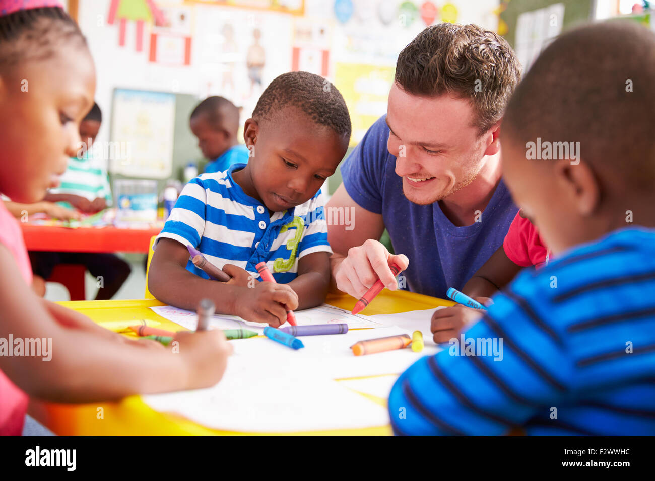 Volunteer teacher helping a class of preschool kids drawing Stock Photo ...