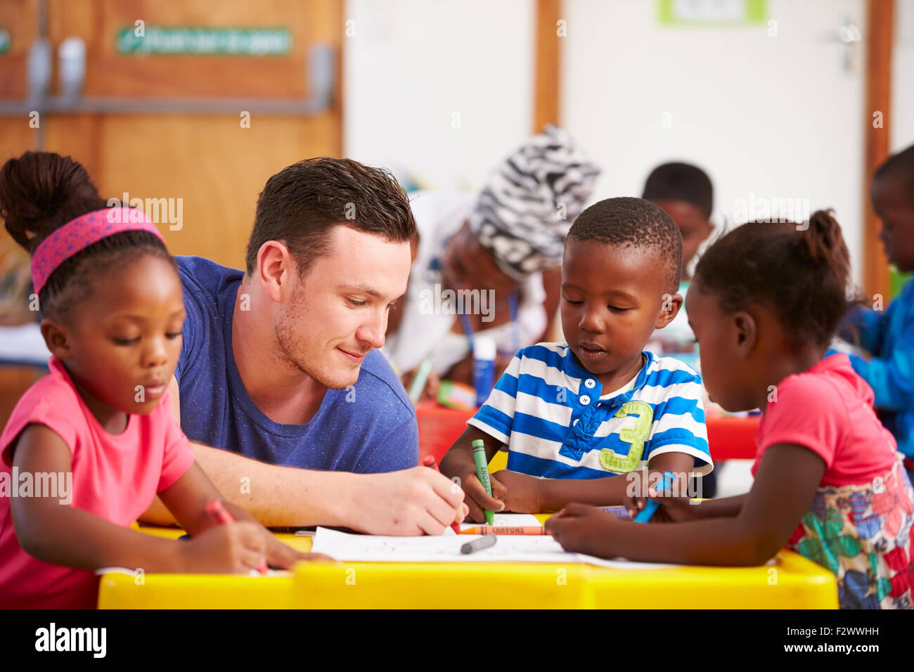 Volunteer teacher sitting with preschool kids in a classroom Stock ...