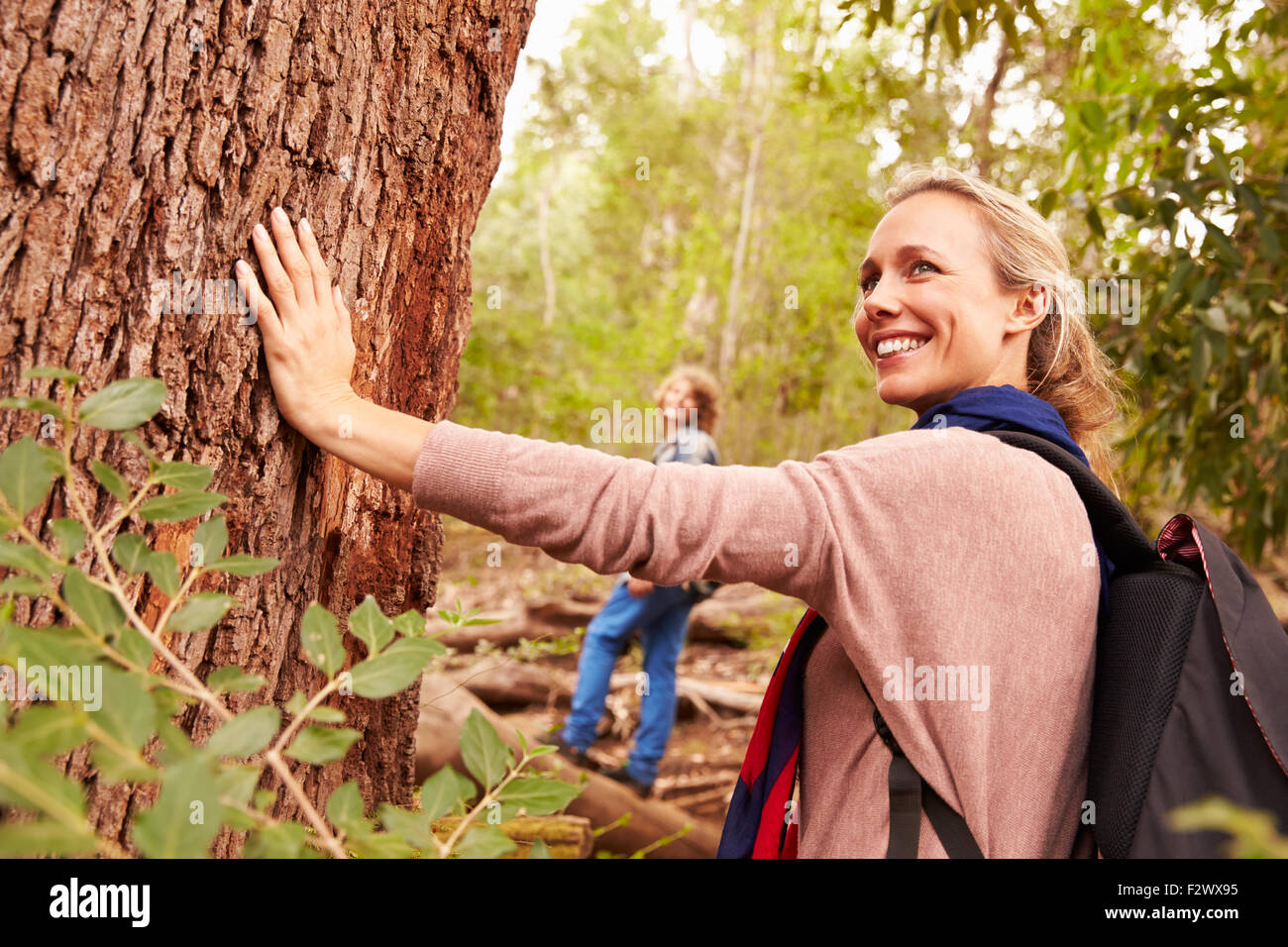 Woman touching a tree in a forest, her son in the background Stock ...