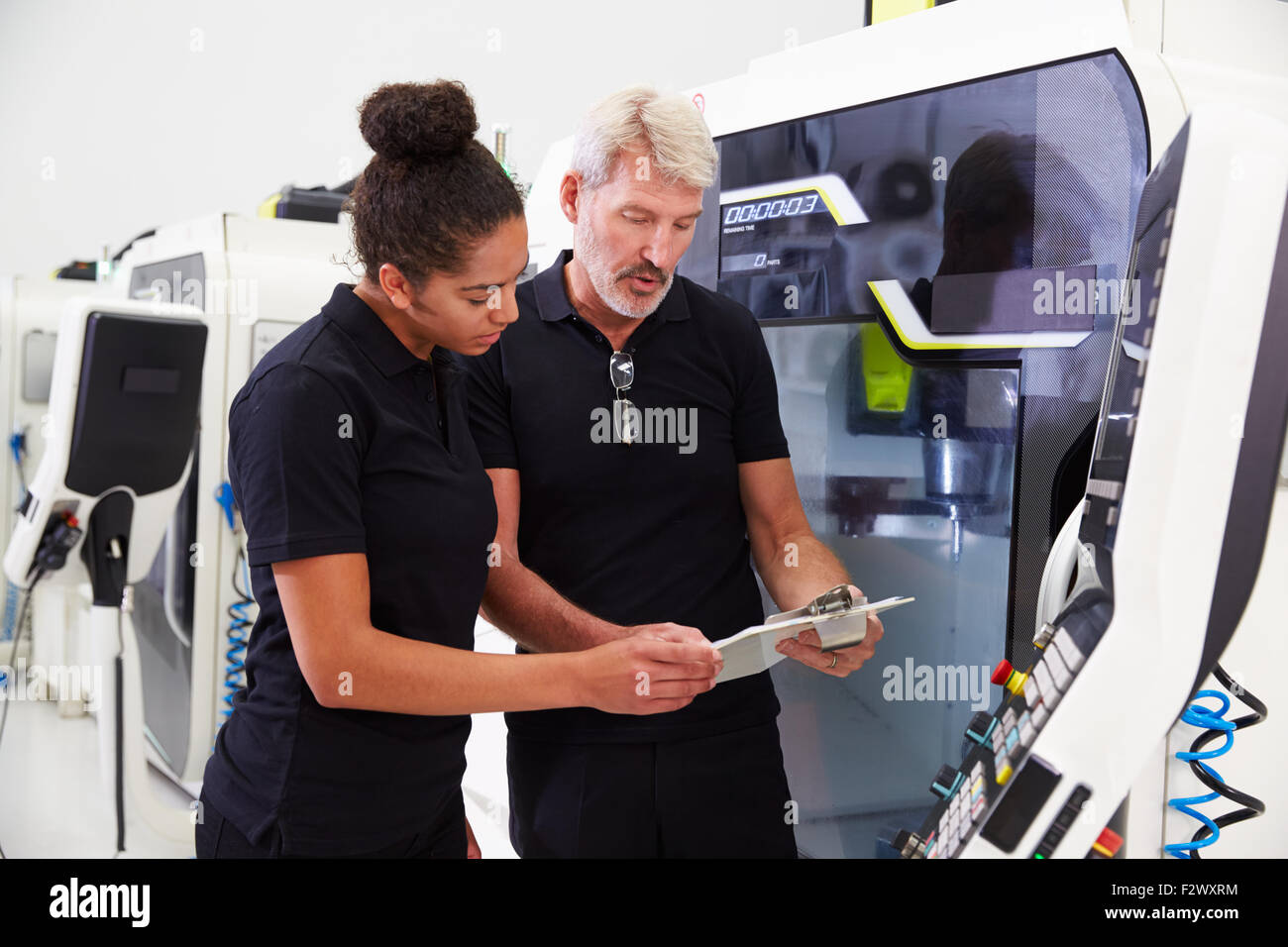 Female Apprentice Working With Engineer On CNC Machinery Stock Photo ...