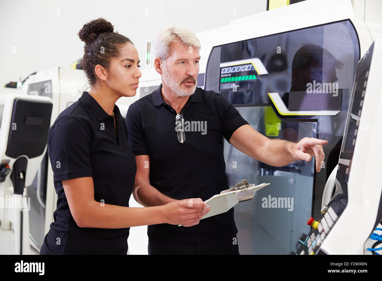 Female Apprentice Working With Engineer On CNC Machinery Stock Photo ...