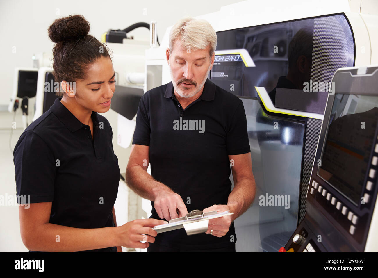 Female Apprentice Working With Engineer On CNC Machinery Stock Photo ...