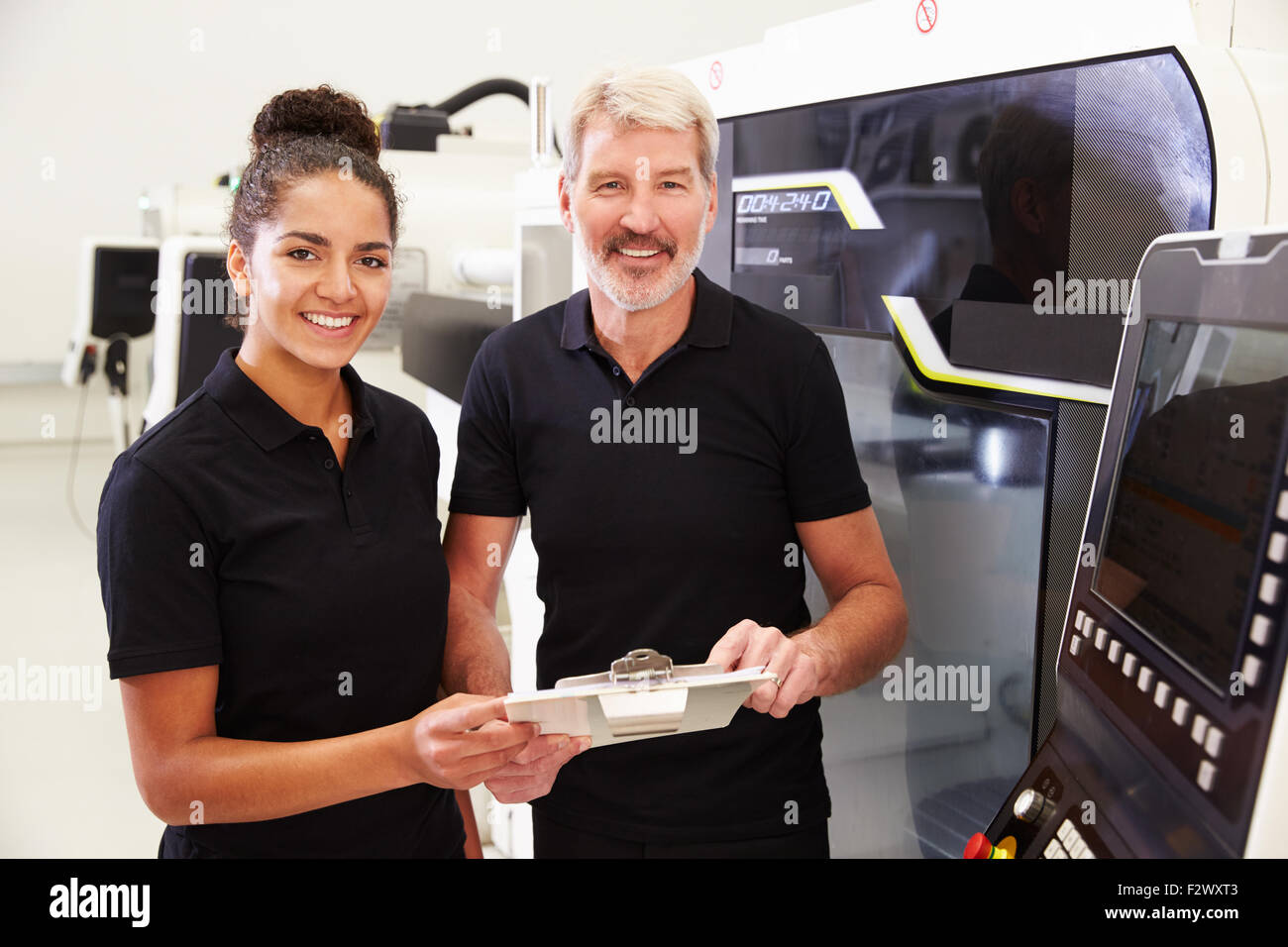 Portrait Of Apprentice Working With Engineer On CNC Machine Stock Photo ...
