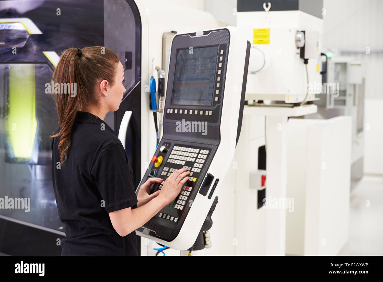 Female Engineer Operating CNC Machinery On Factory Floor Stock Photo ...