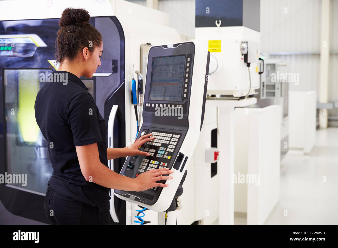 Female Engineer Operating CNC Machinery On Factory Floor Stock Photo ...