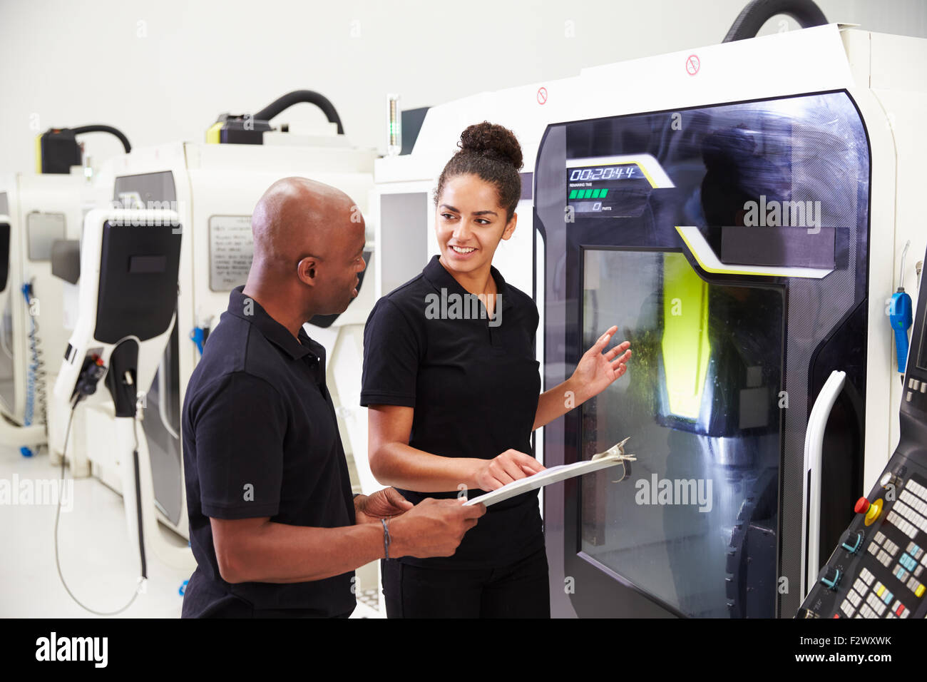 Female Apprentice Working With Engineer On CNC Machinery Stock Photo ...