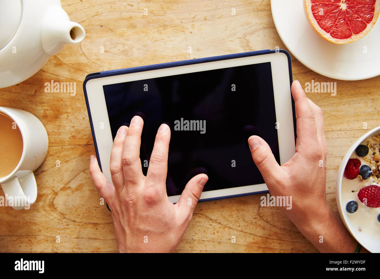 Person Looking At Digital Tablet Whilst Eating Breakfast Stock Photo ...