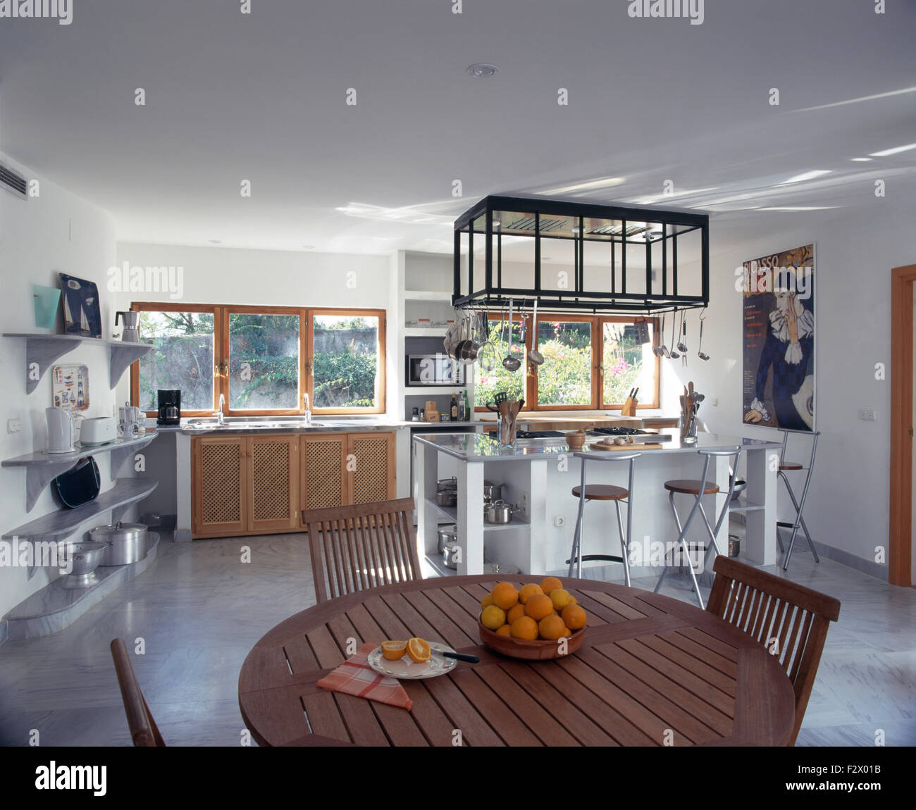 Wooden table and chairs in a modern white Spanish kitchen with pans ...