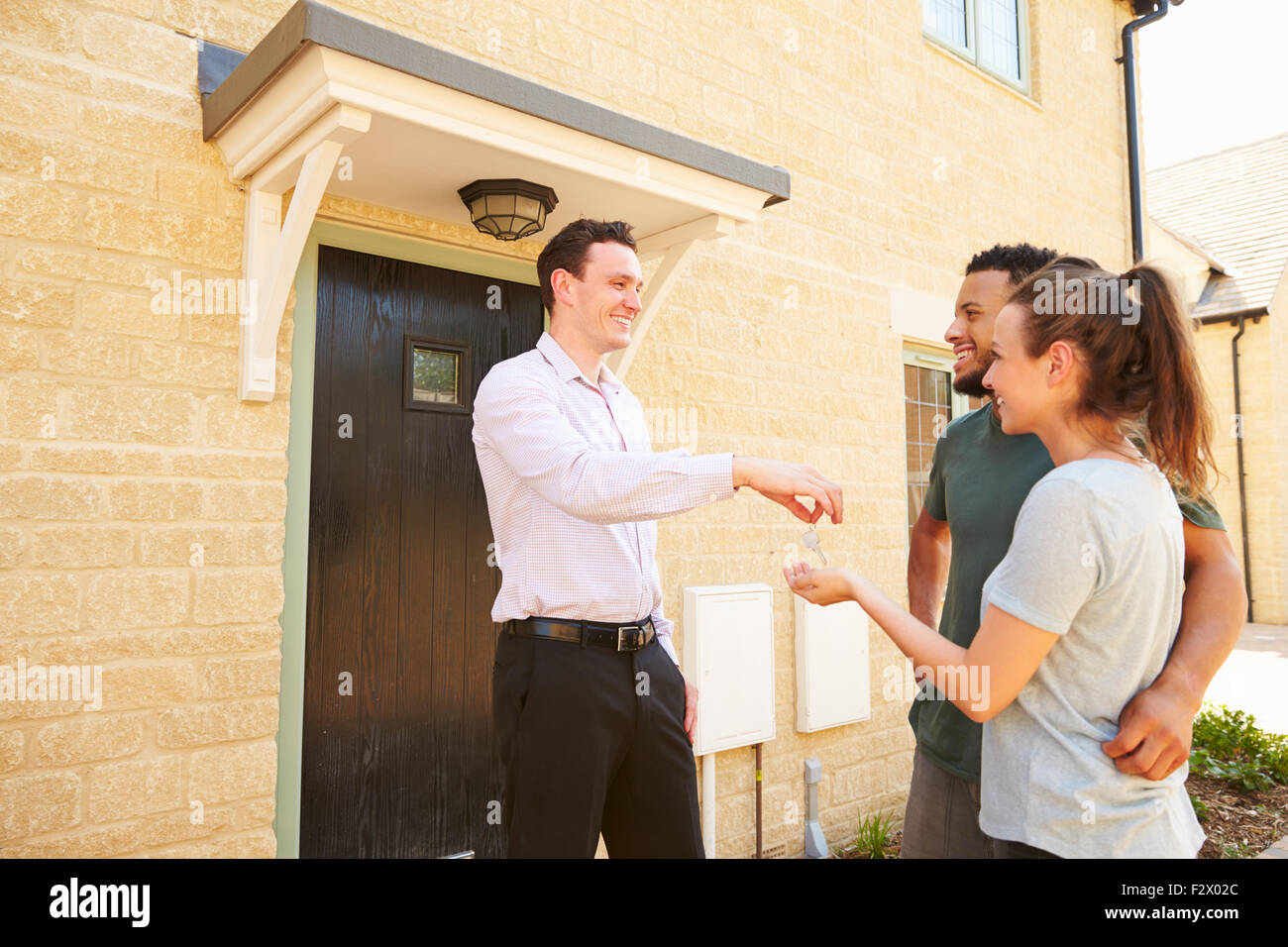 Real estate agent giving house keys to new property owners Stock Photo ...