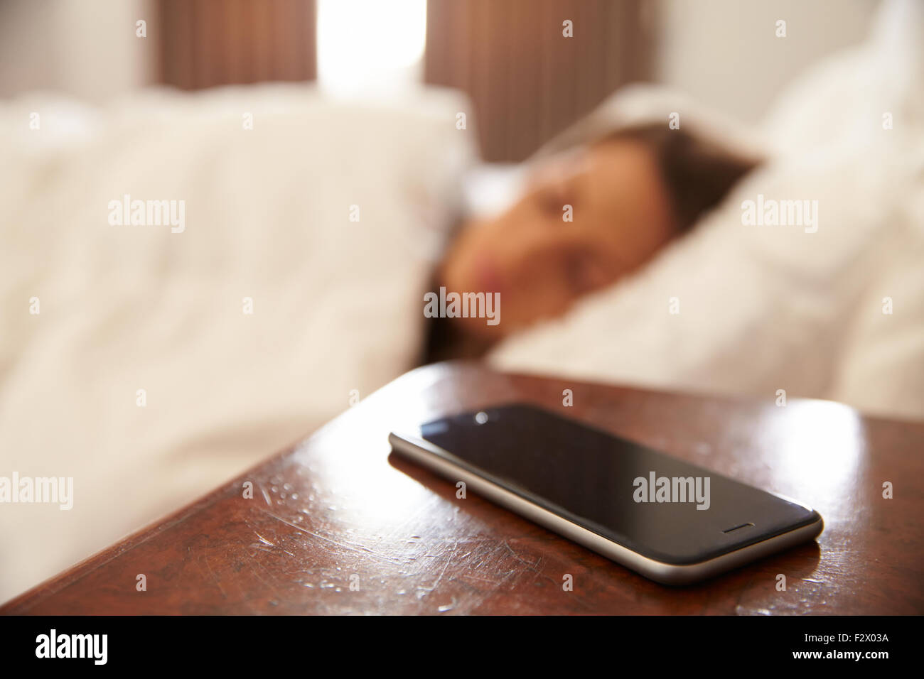 Woman Asleep In Bed With Mobile Phone On Bedside Table Stock Photo - Alamy