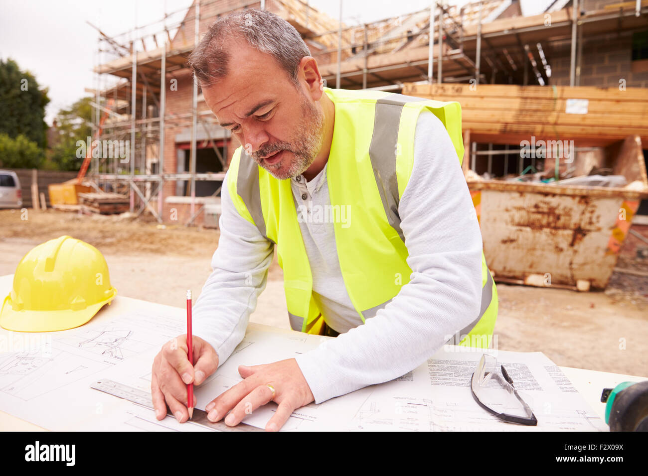 Construction Worker Looking At Plans On Building Site Stock Photo - Alamy