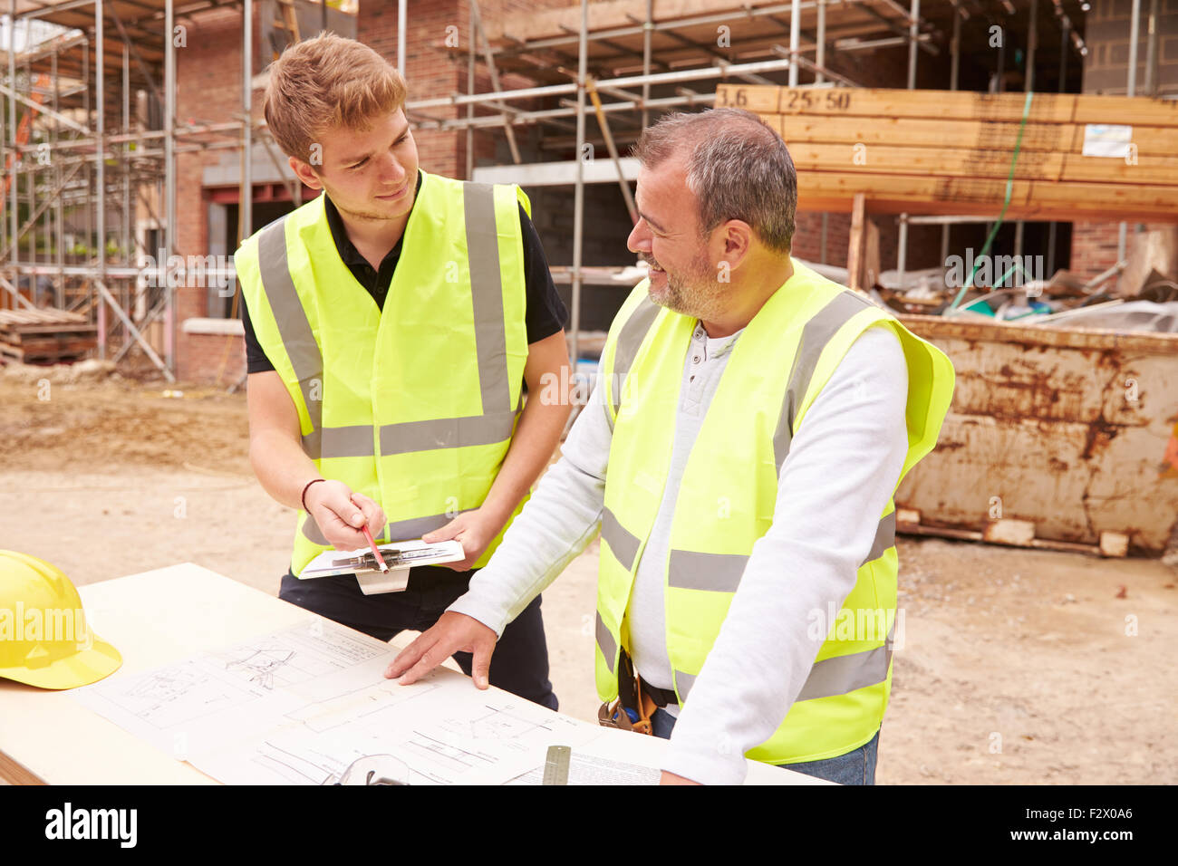 Builder On Building Site Discussing Work With Apprentice Stock Photo ...