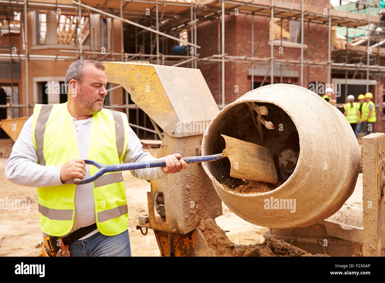 Construction Worker On Building Site Mixing Cement Stock Photo - Alamy