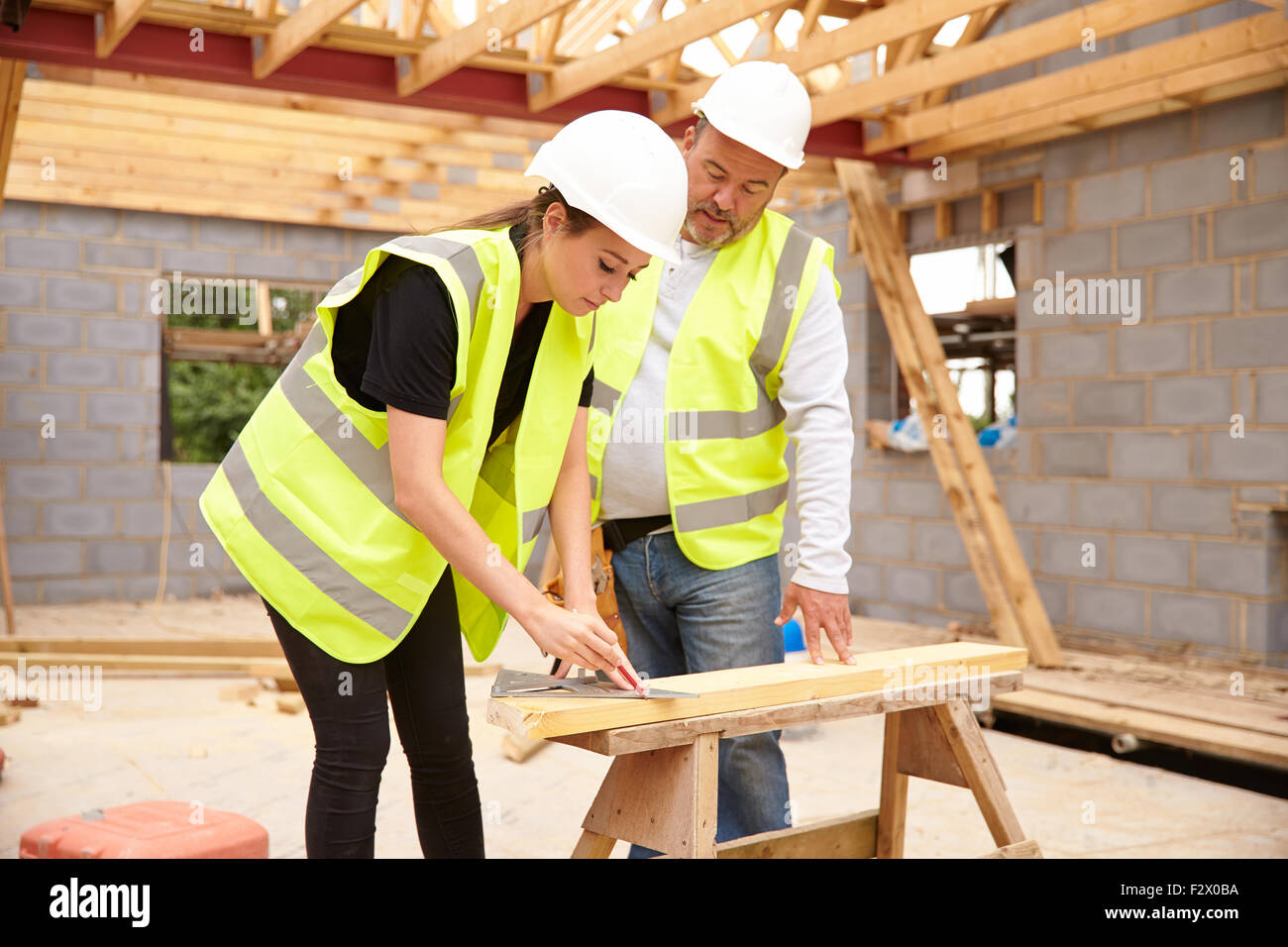 Carpenter With Female Apprentice Working On Building Site Stock Photo ...