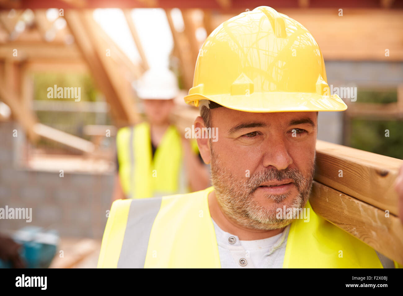 Builder And Apprentice Carrying Wood On Construction Site Stock Photo ...