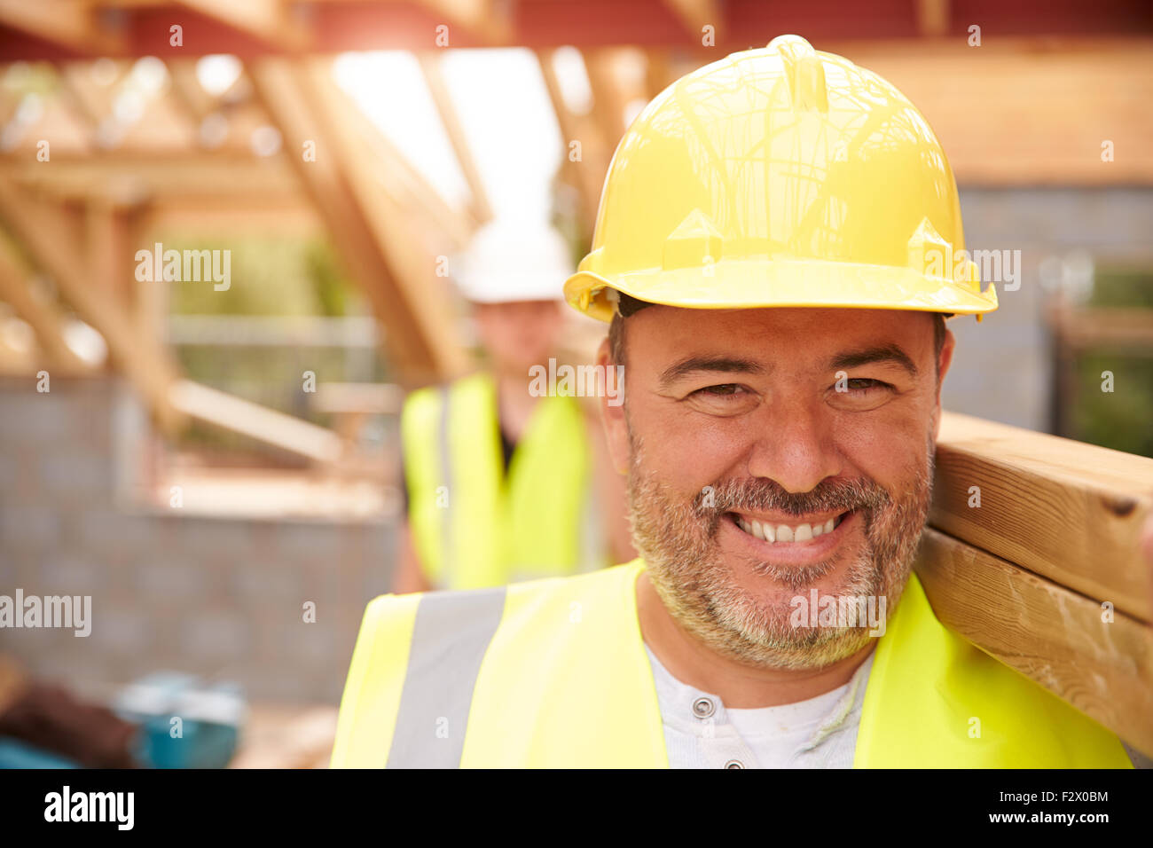 Builder And Apprentice Carrying Wood On Construction Site Stock Photo ...