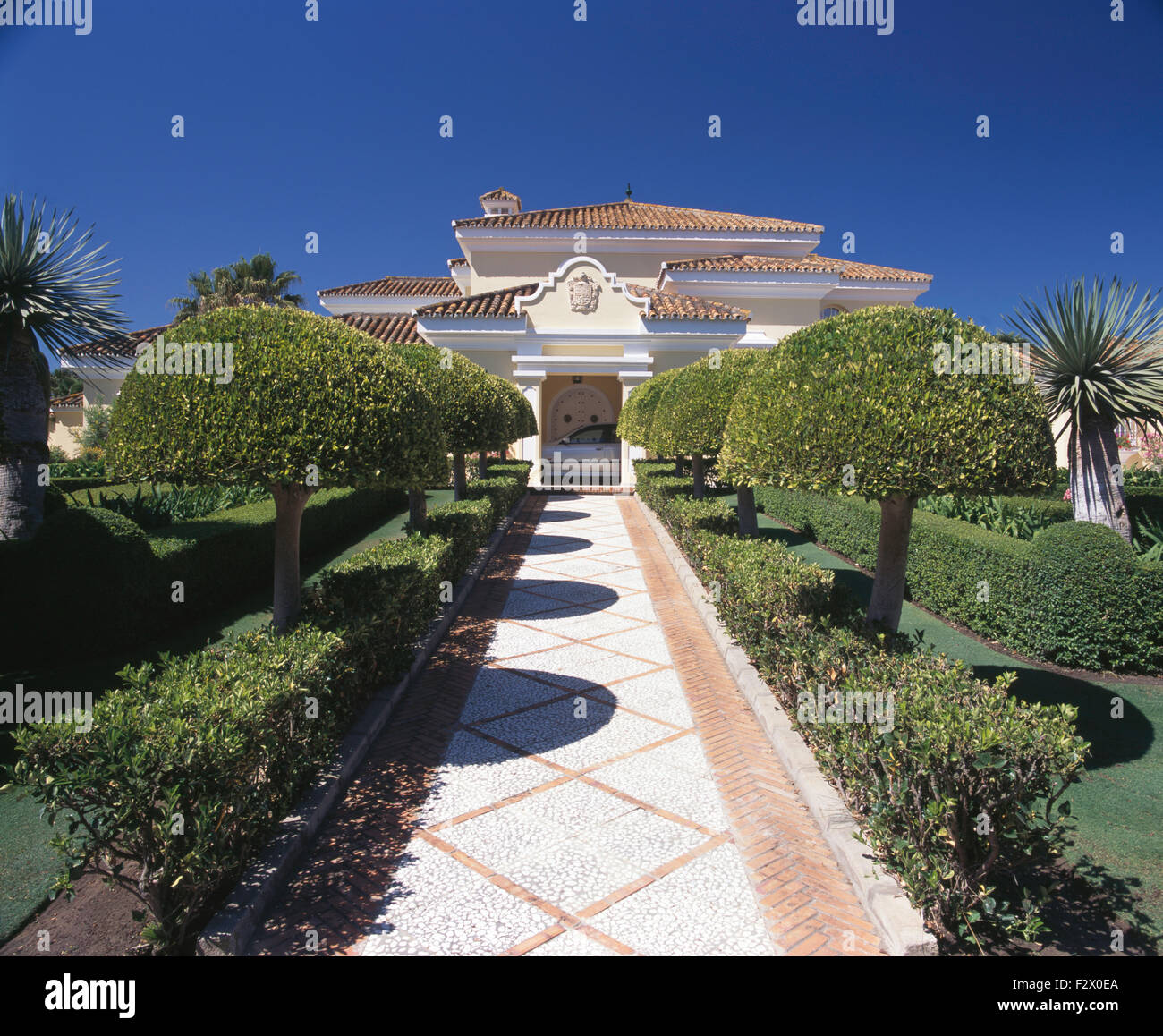 Clipped trees and low hedge on either side of pebble paved path to ...