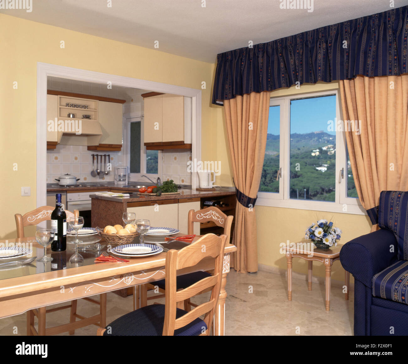 Table Set For Lunch In Spanish Kitchen With Blue Pelmet On Peach Drapes table-set-for-lunch-in-spanish-kitchen-with-blue-pelmet-on-peach-drapes