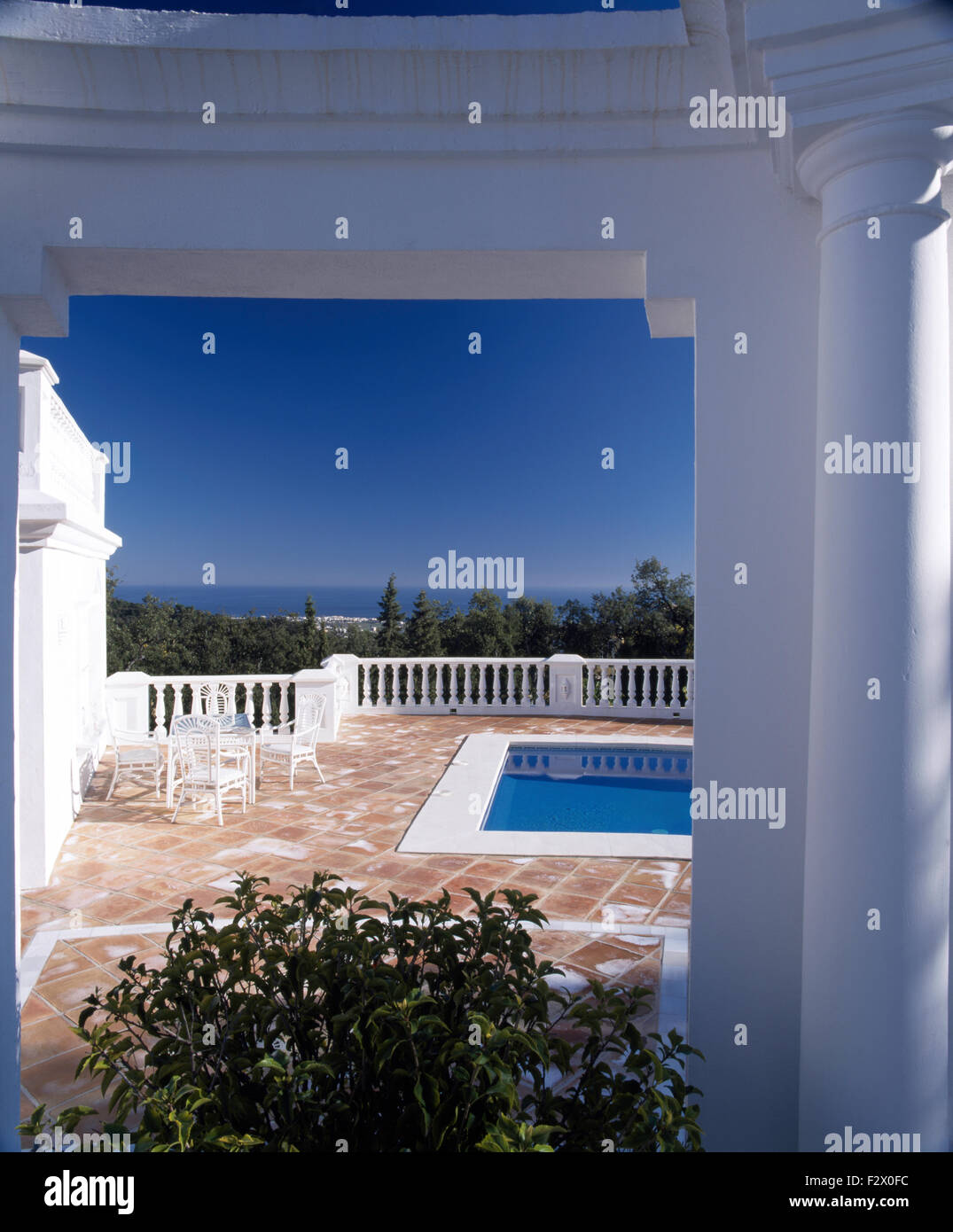 Exterior of Spanish villa with view through columns of swimming pool ...