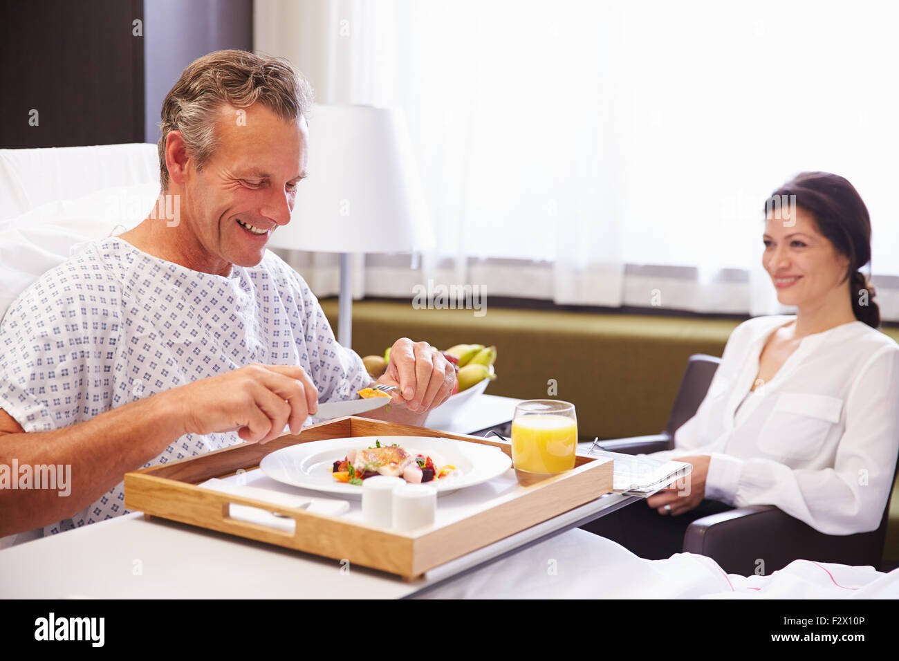 Male Patient In Hospital Bed Eating Meal From Tray Stock Photo - Alamy