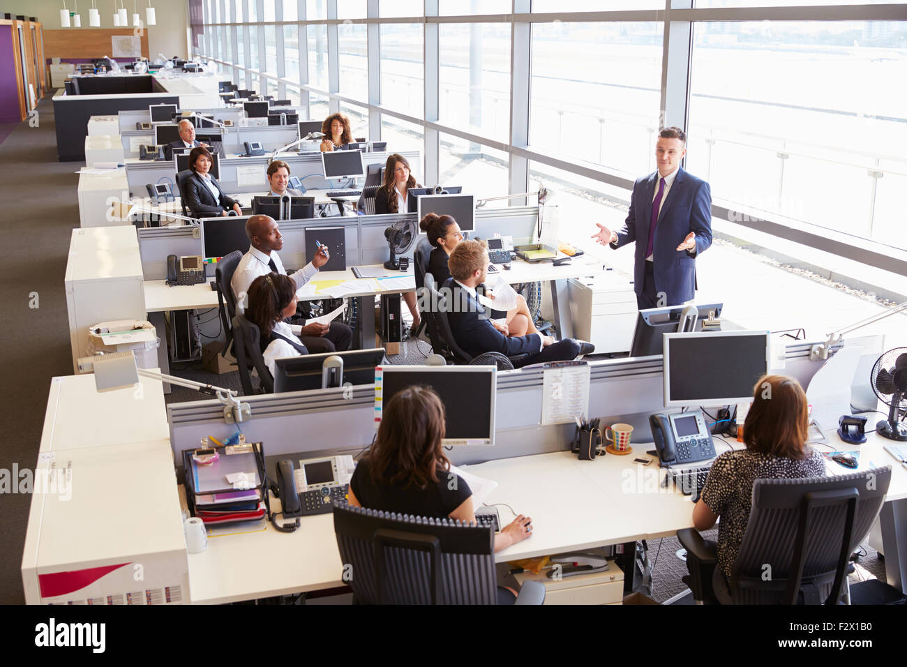 Young male manager addressing workers in open plan office Stock Photo ...