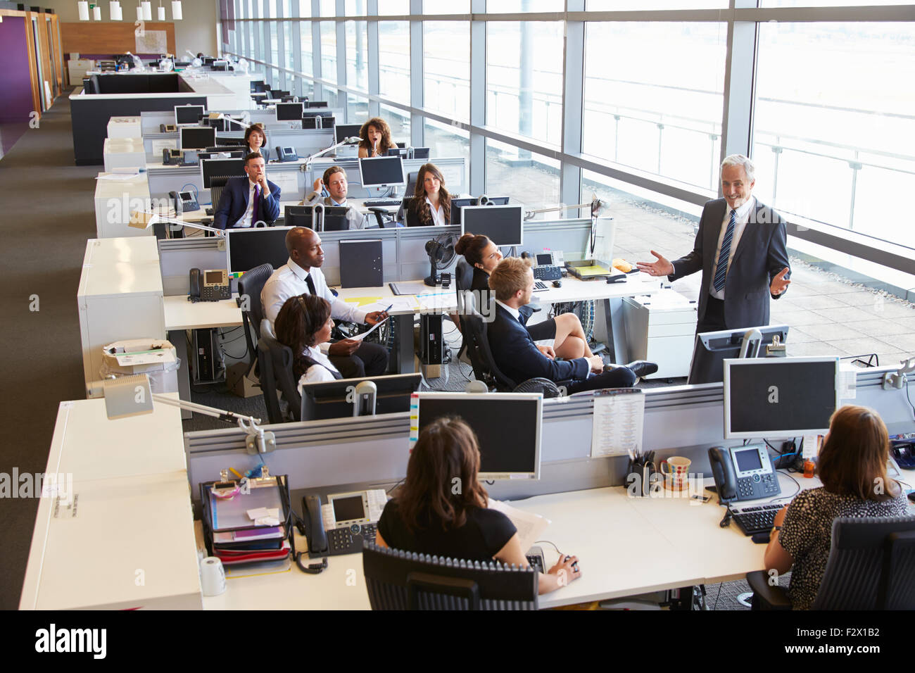 Senior male manager addressing workers in open plan office Stock Photo ...