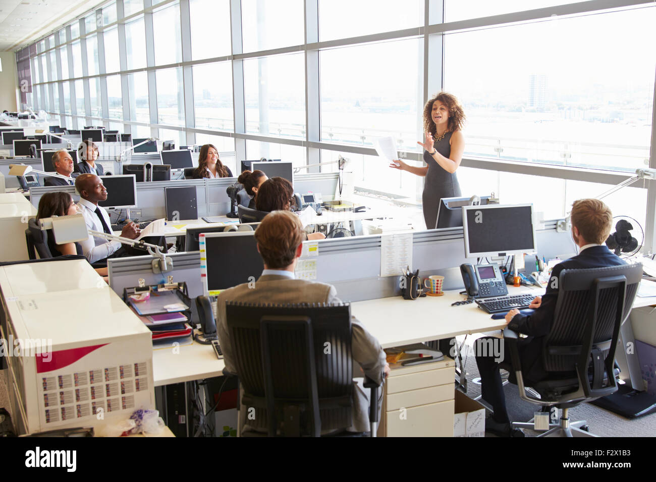 Female manager addressing workers in open plan office Stock Photo - Alamy