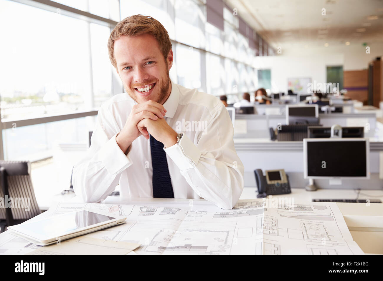 Young architect at work in an office, smiling to camera Stock Photo - Alamy