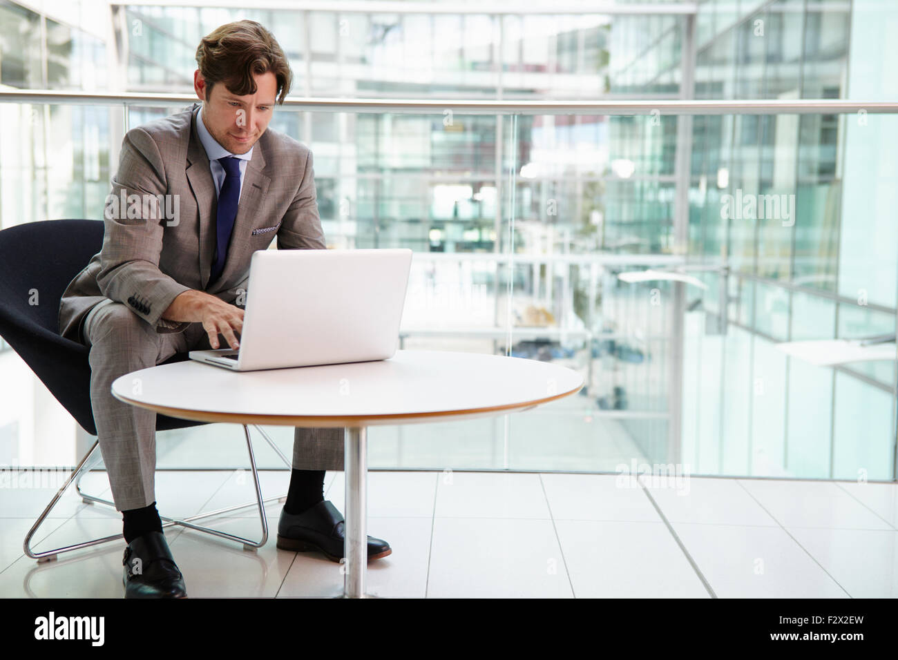 Corporate businessman using laptop computer, full length Stock Photo ...