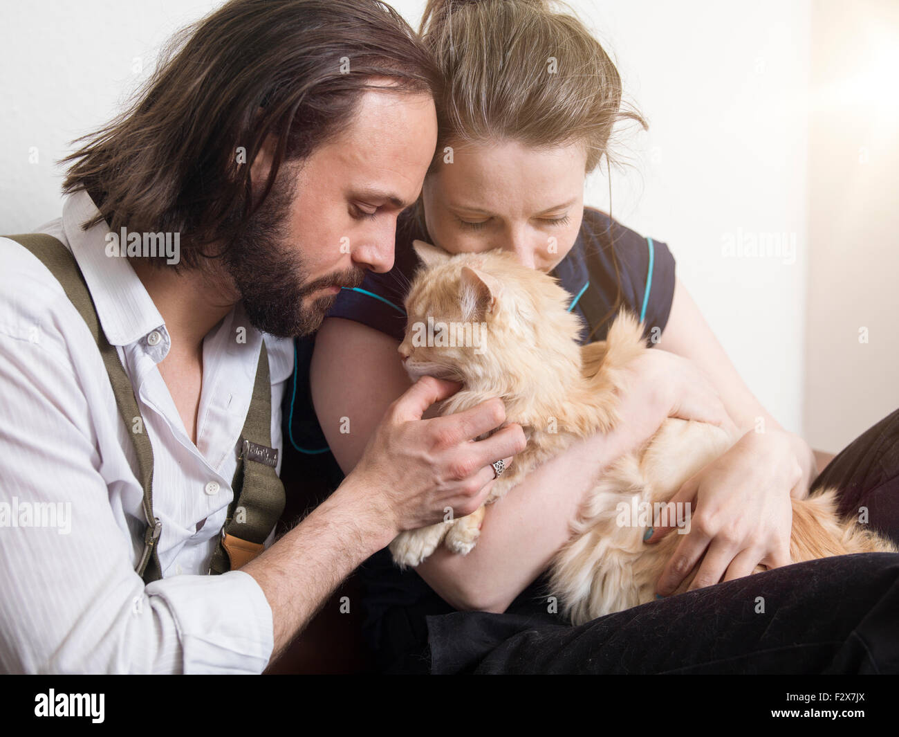 Couple cuddling with their Maine Coon at home Stock Photo - Alamy