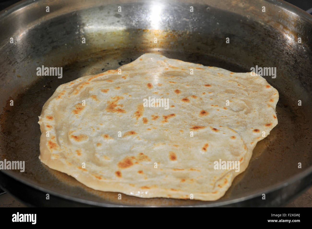preparing a flat bread Pita on a Saj - an iron dome shaped pan that is ...