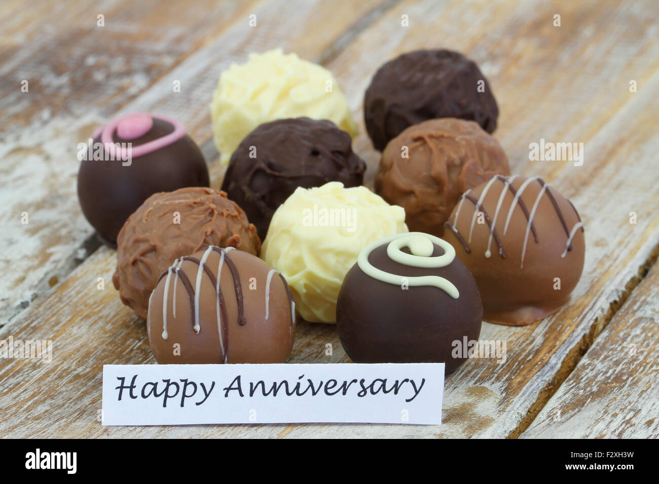 Happy Anniversary card with assorted chocolates on rustic wooden ...