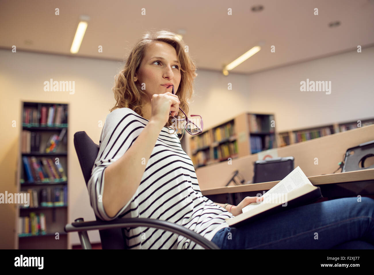 student wondering or thinking about something. holding glasses in hand ...