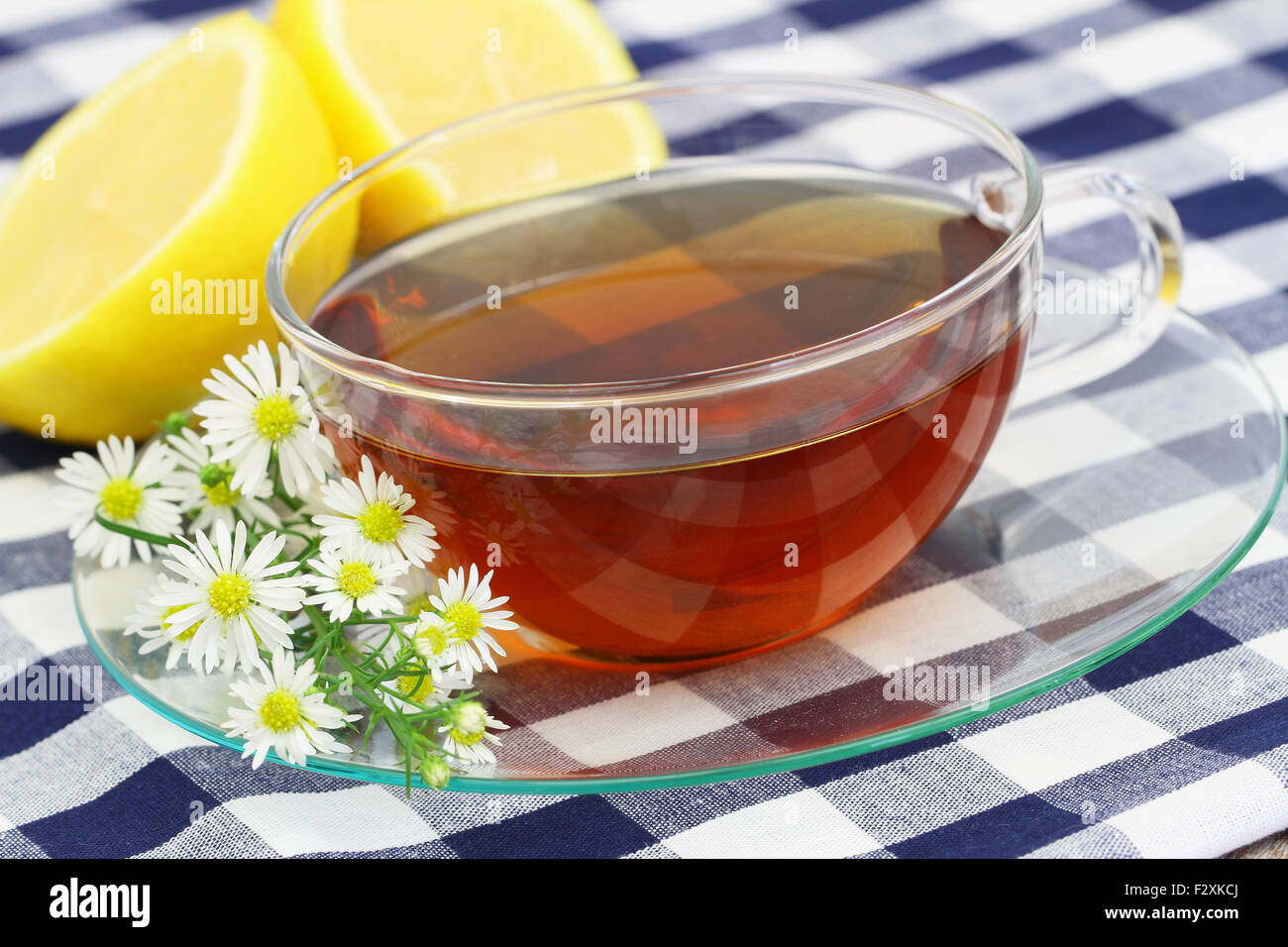 Chamomile tea with lemon and fresh chamomile flowers on checkered cloth ...