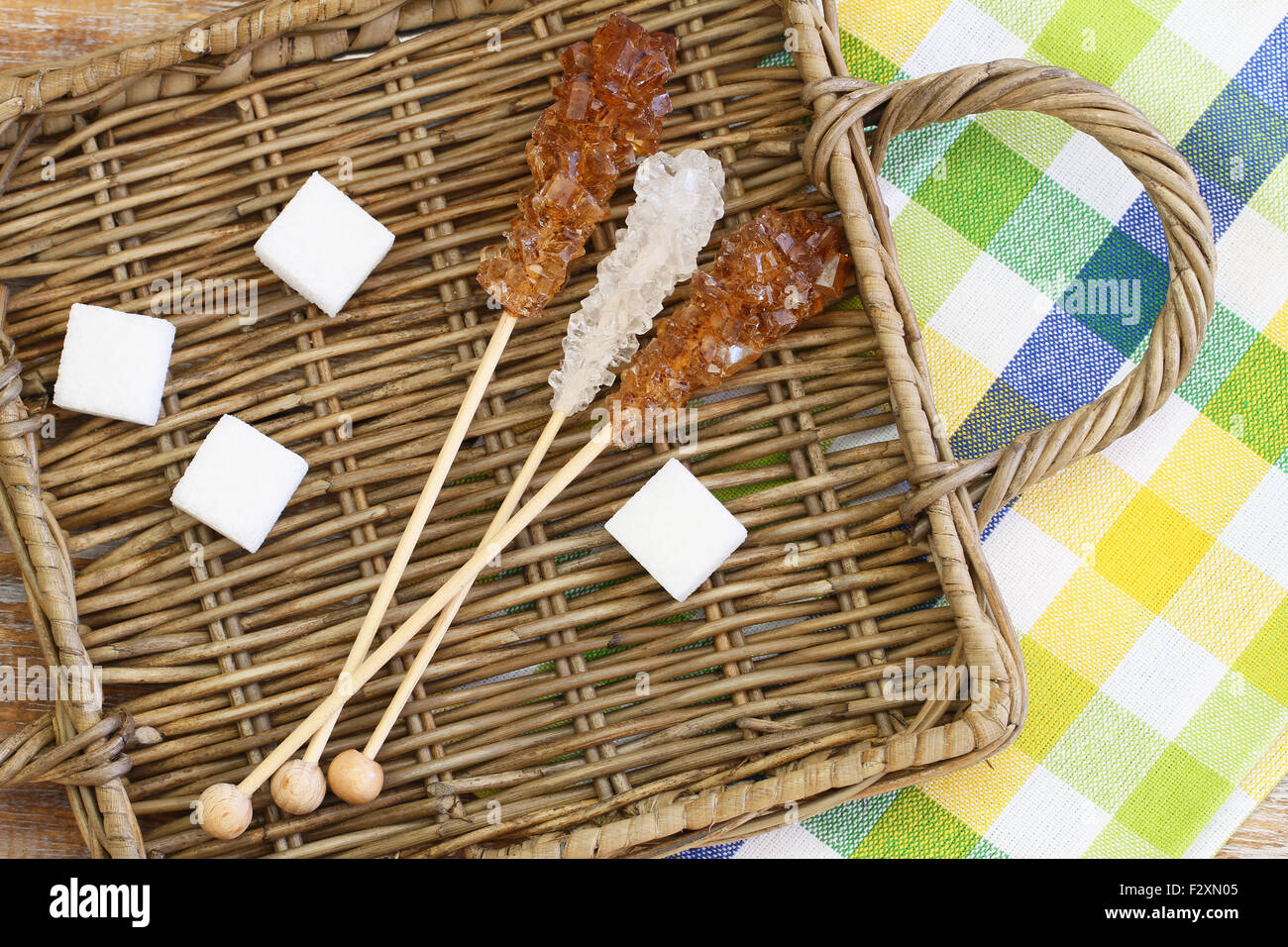White sugar cubes and white and brown sugar sticks on wicker tray Stock ...