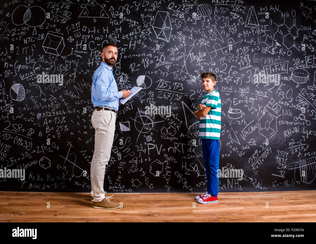 Young hipster school teacher with his pupil in front of big blackboard ...
